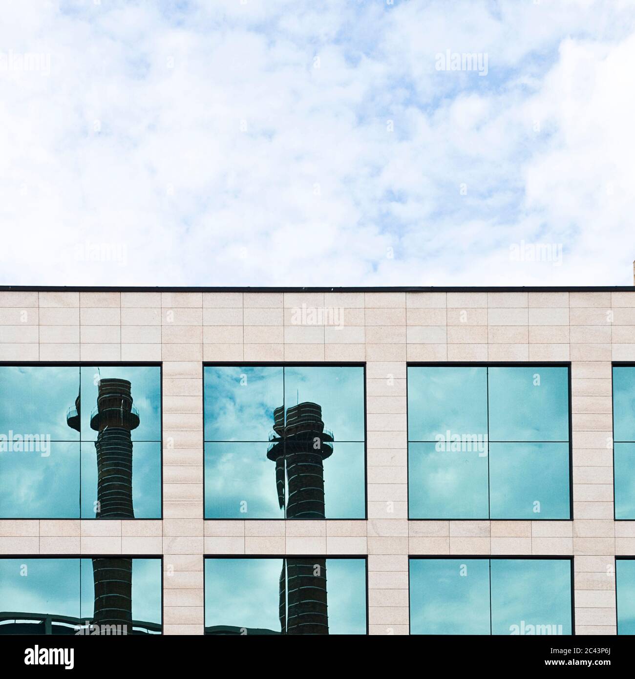 Two towers are reflected in the windows of an office building ...