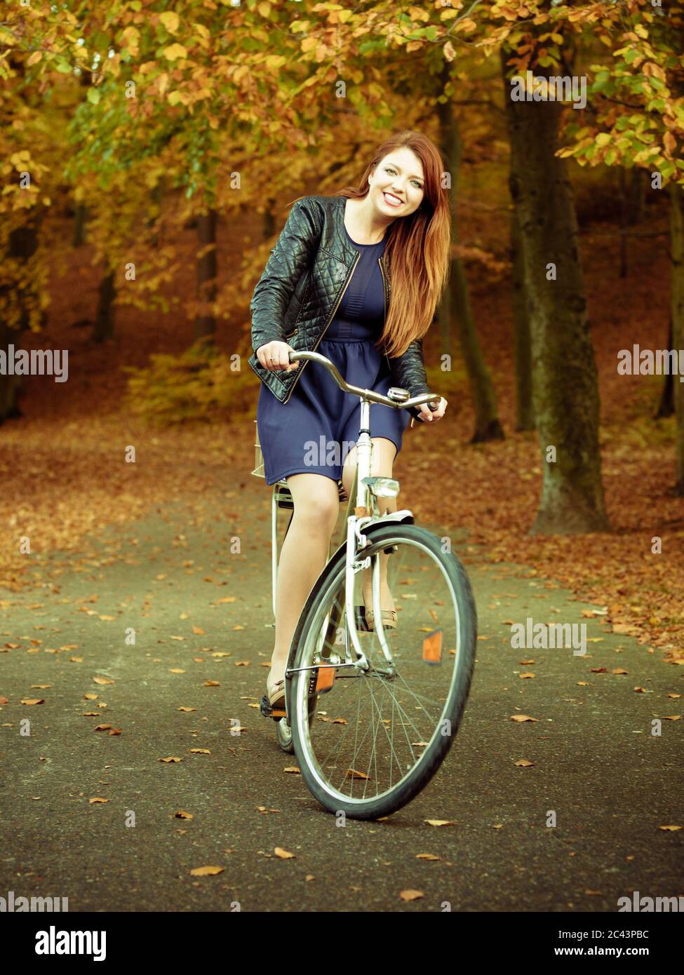 Nature, people concept. Young female is riding bike in the park. Golden ...