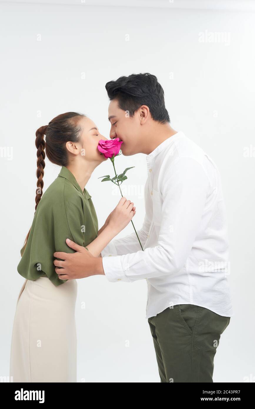 Beautiful elegant couple is kissing behind roses Stock Photo - Alamy