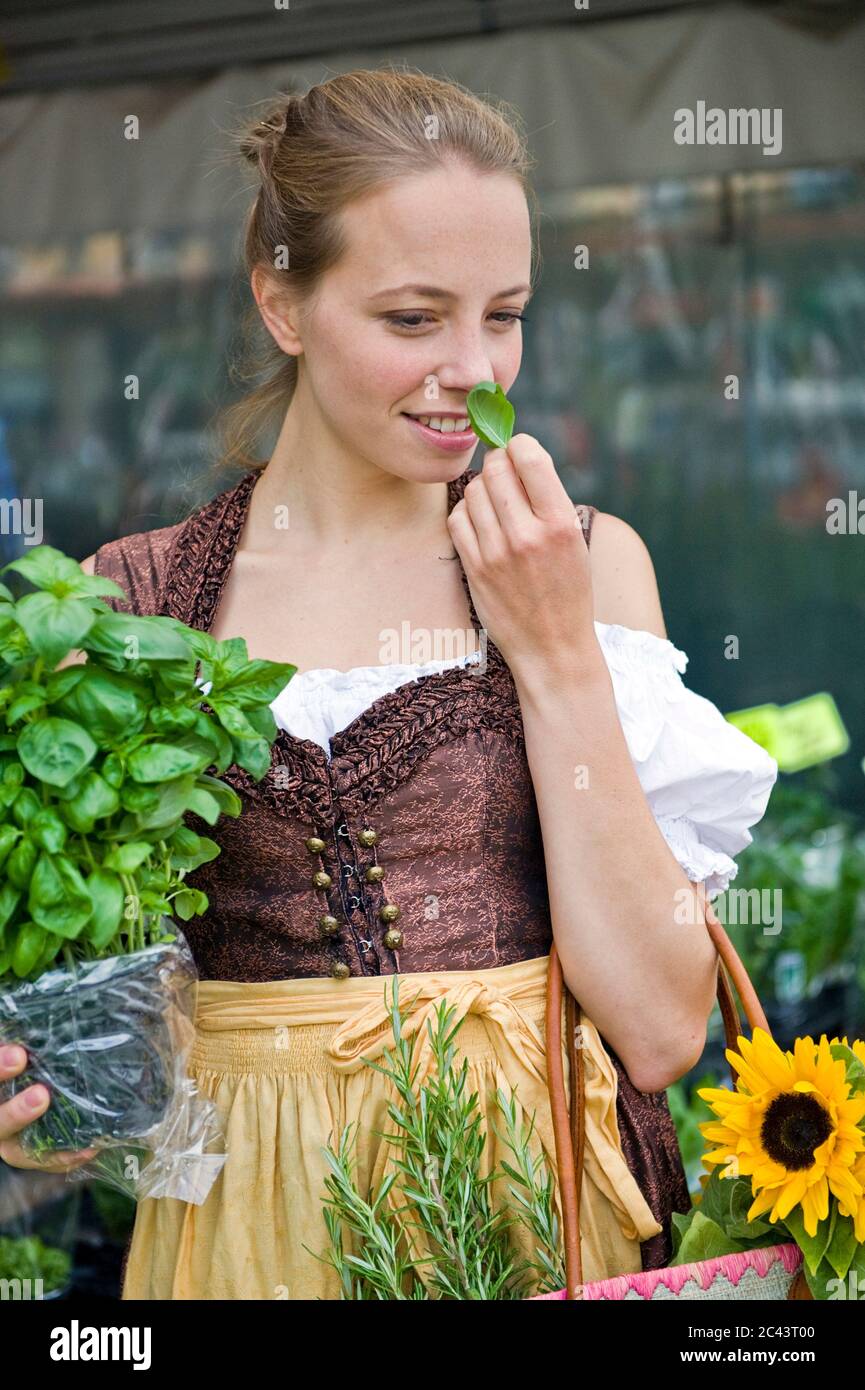 Young woman in dirndl smells of basil Stock Photo - Alamy