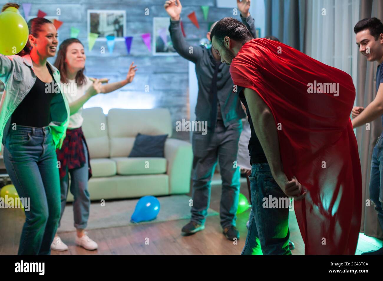 Group of friends cheering up for men with superhero cape at the party ...