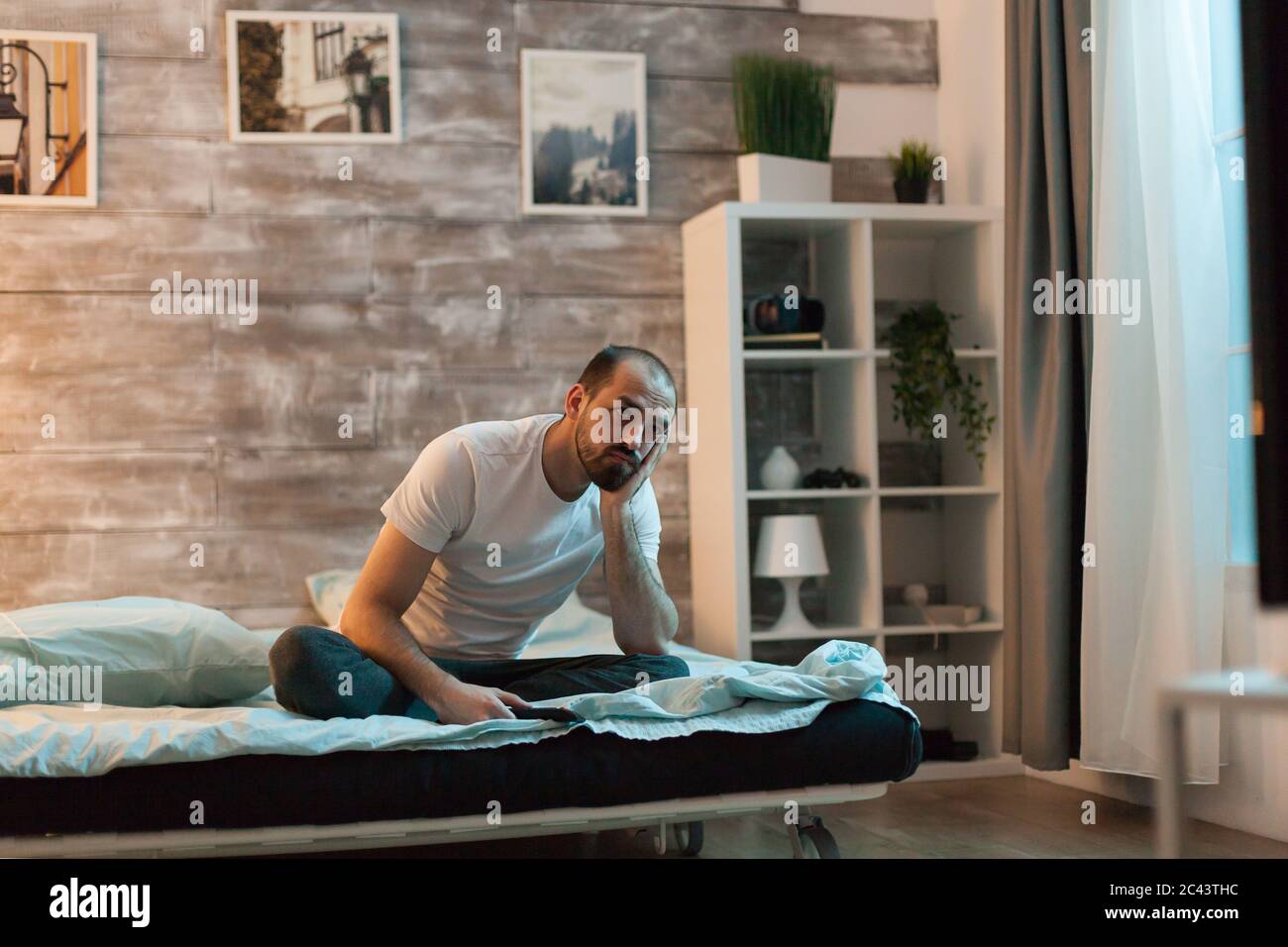 Tired man watching tv late at night wearing pajamas Stock Photo - Alamy
