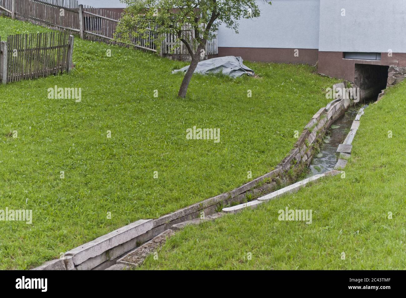 Bach flows through under a house Stock Photo - Alamy