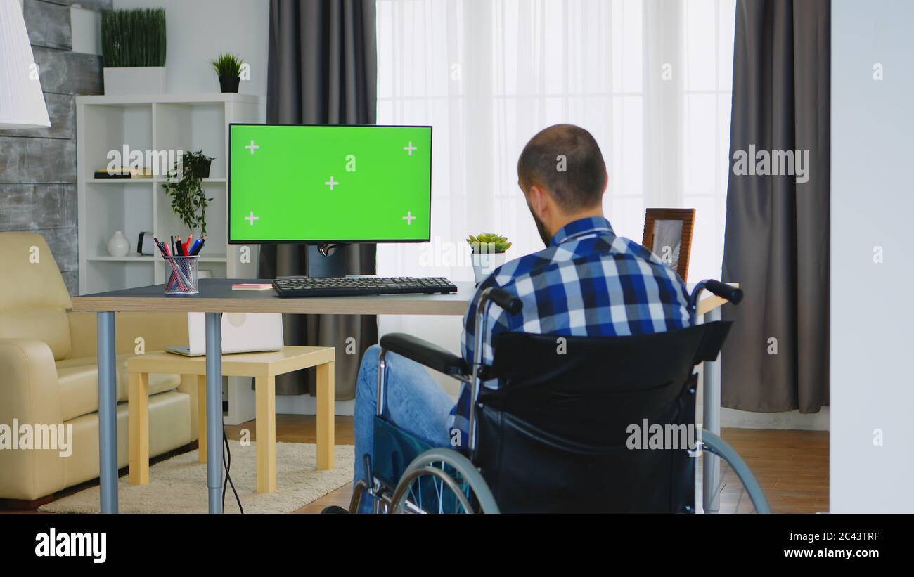 Invalid man in wheelchair working on computer with green screen Stock ...
