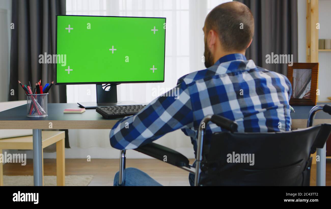 Invalid man in wheelchair working on computer with green screen Stock ...