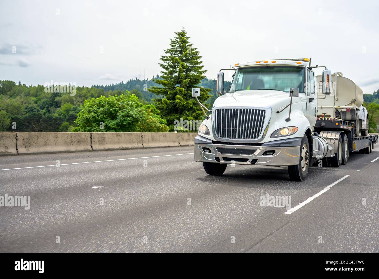 Big rig white powerful day cab semi truck transporting another semi ...