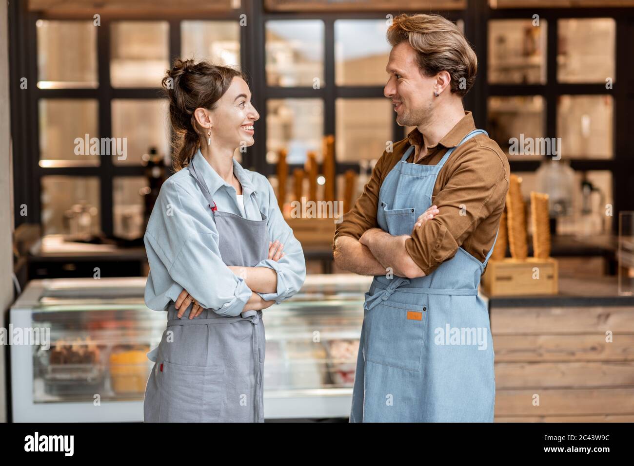 Portrait of a two cheerful employees of a cafe or small shop standing ...