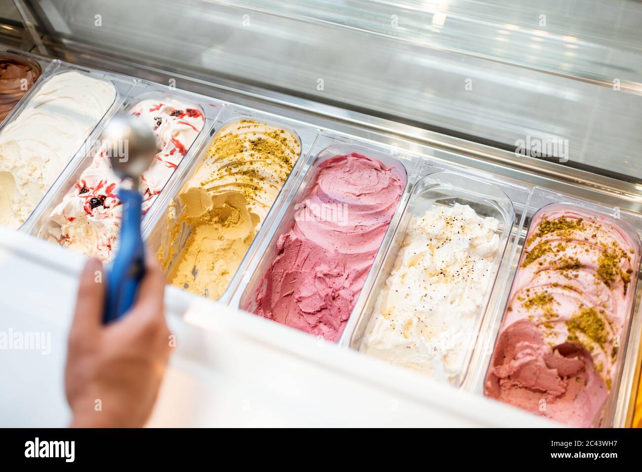 Salesman picking ice cream with a spoon from refrigerator in the store ...