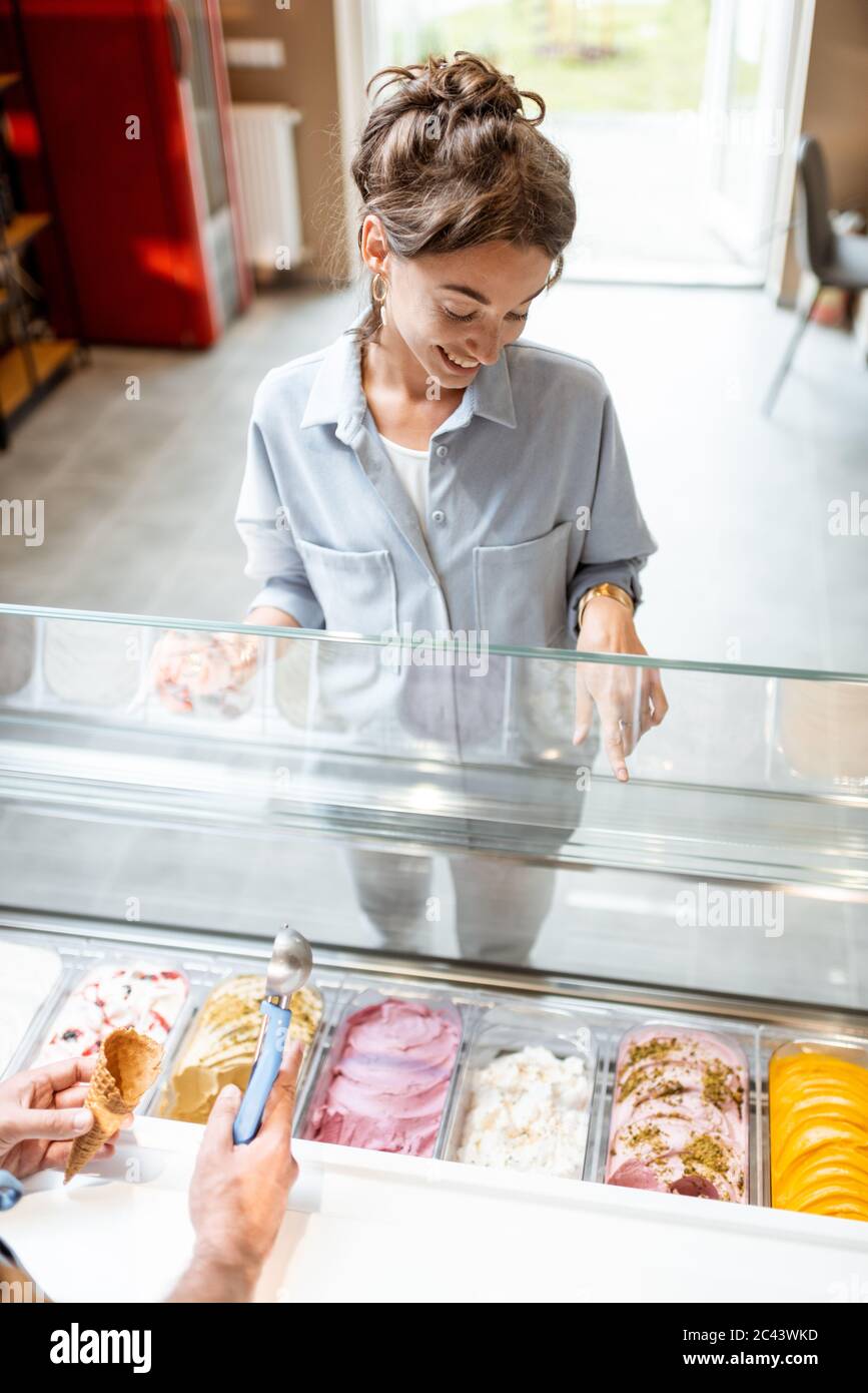 Young female client choosing an ice cream flavor, standing with a ...