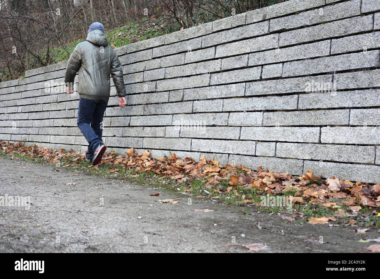 Pedestrian walks along a stone wall, Munich, Bavaria, Germany Stock ...