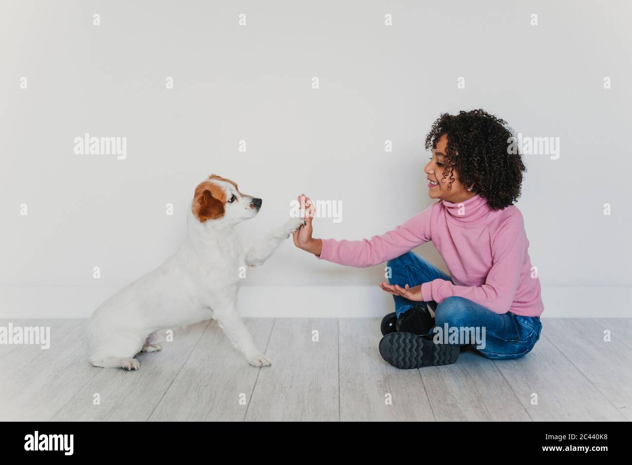 Smiling little girl sitting on the floor with her dog giving paw Stock ...