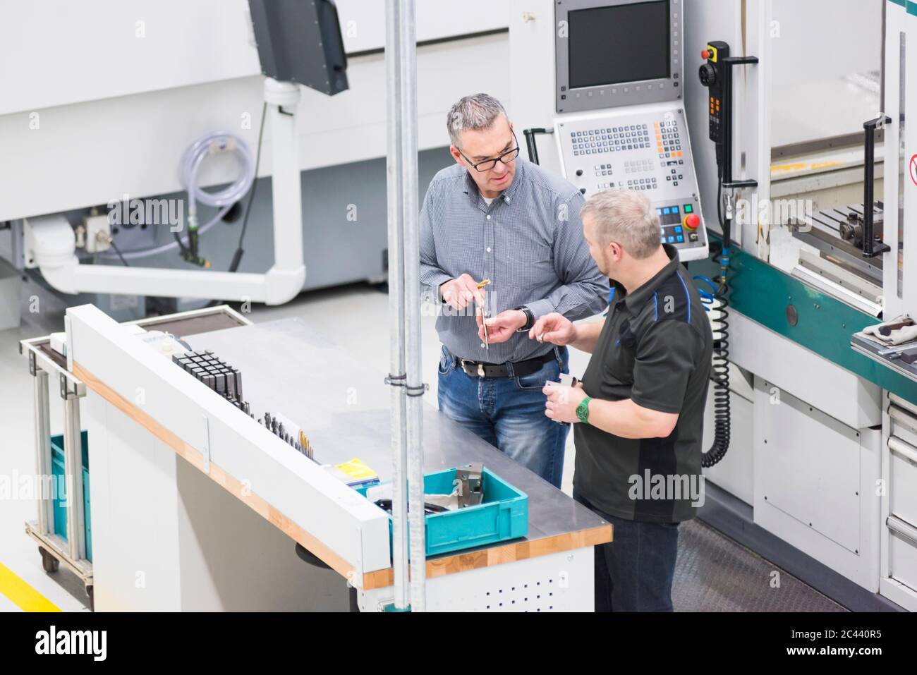 Two men talking at a machine in a factory Stock Photo - Alamy