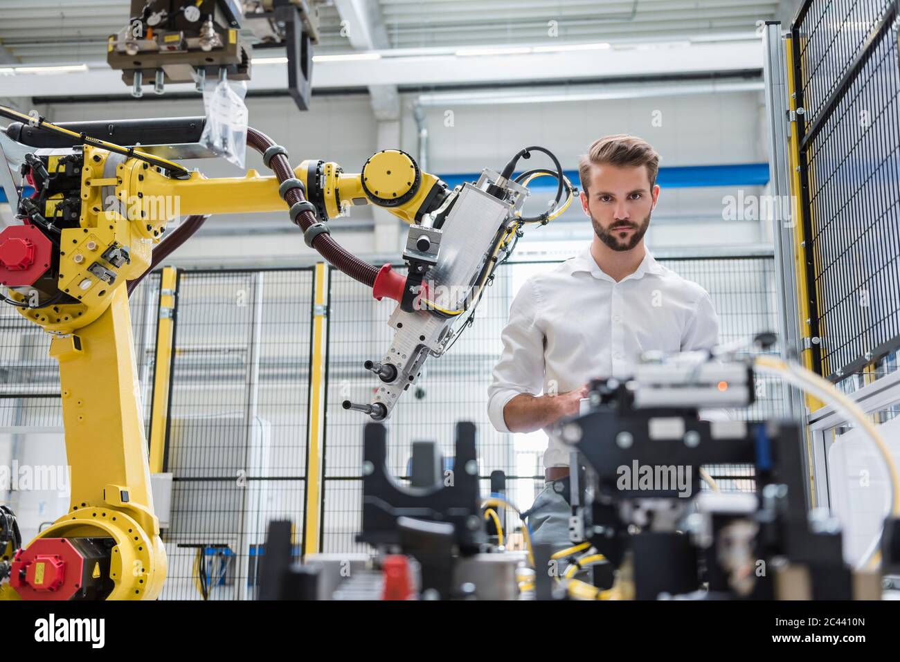 Confident male robotics expert looking at machinery in automated ...