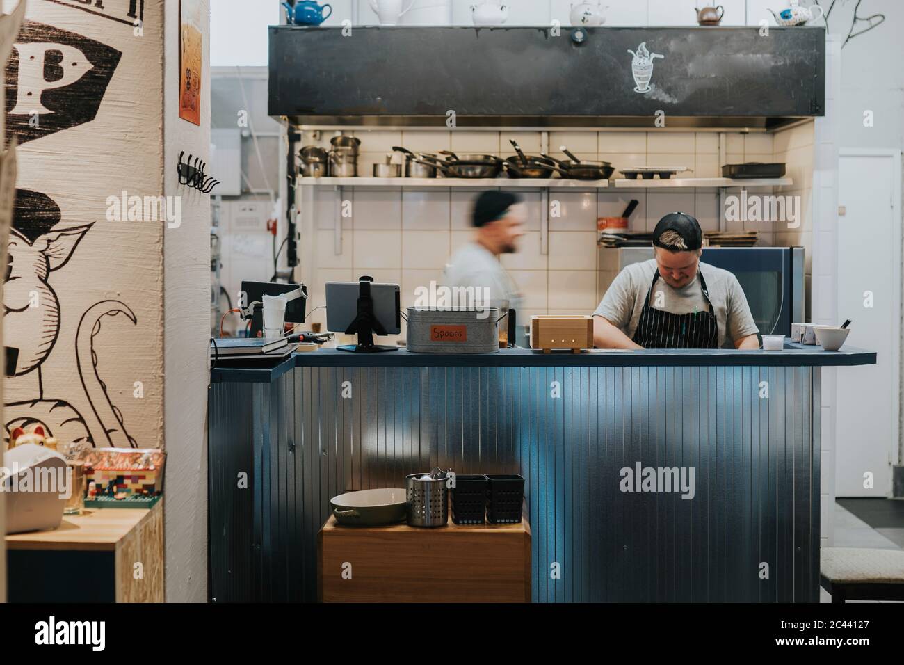 Male chefs preparing food behind counter at illuminated restaurant ...