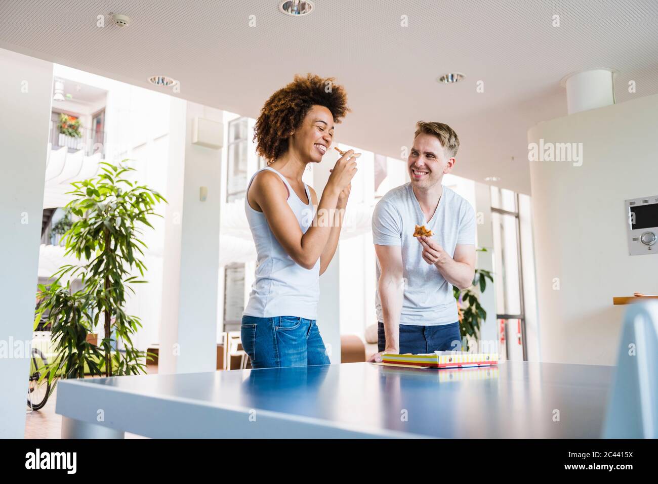 Young business people sharing pizza for lunch in a modern office with ...
