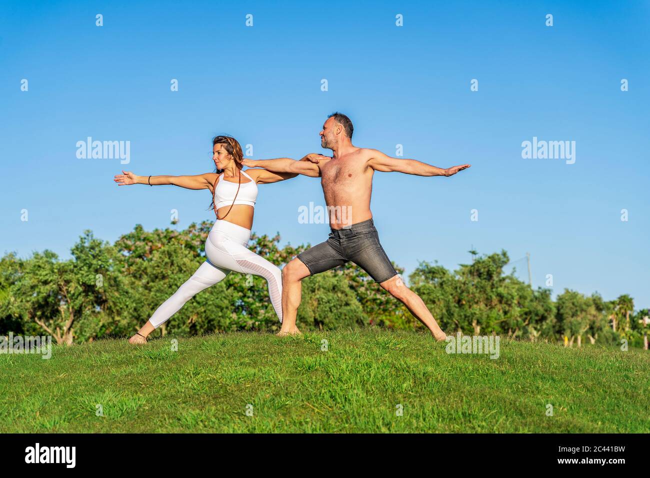 Mature couple doing yoga on lawn in sunshine together Stock Photo - Alamy