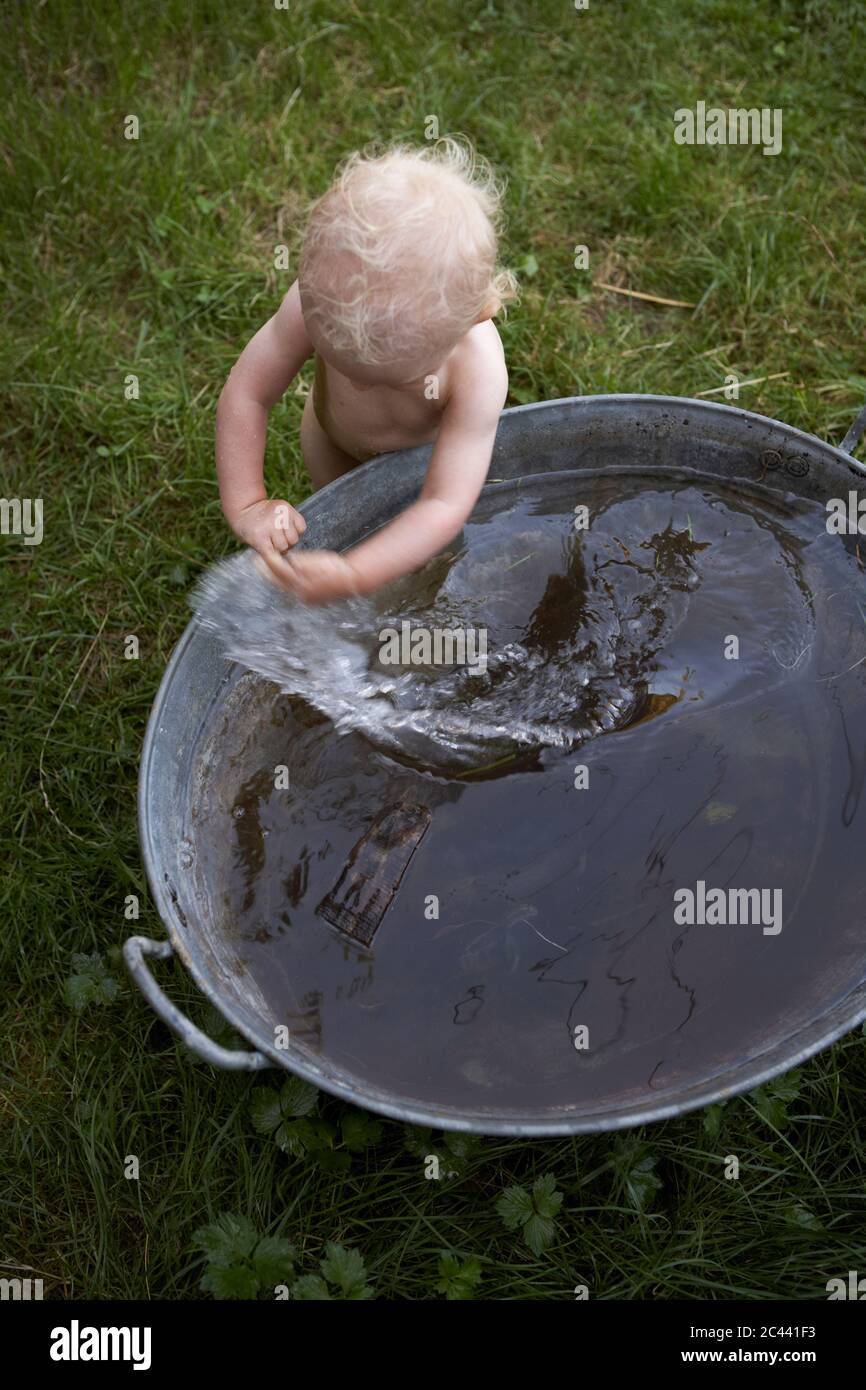 Little boy plays with water in the trough Stock Photo - Alamy