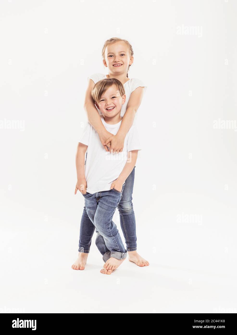 Portrait of smiling girl and her younger brother standing in front of ...