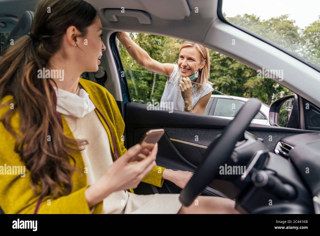 Two women talking through car window Stock Photo - Alamy