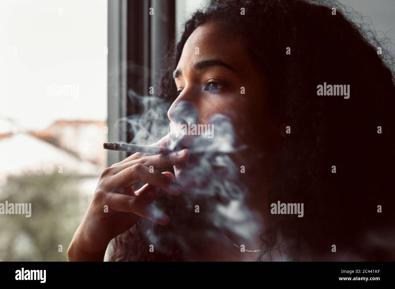 Woman smoking by window hi-res stock photography and images - Alamy