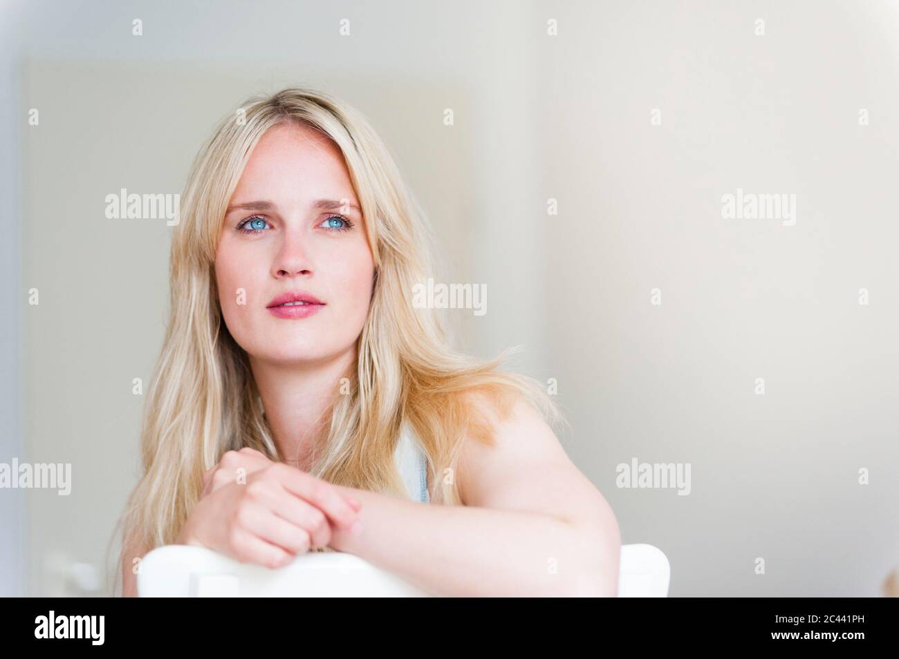 Portrait of blond woman leaning on back rest looking at distance Stock ...