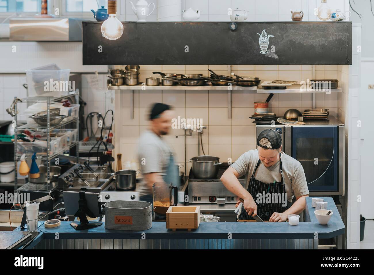 Male chefs cooking behind counter at illuminated restaurant kitchen ...