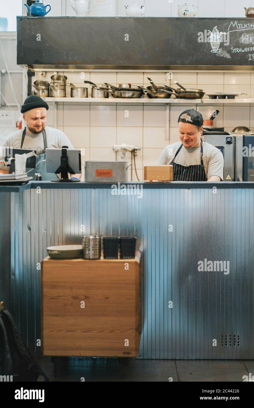 Male chefs preparing food behind kitchen counter in restaurant Stock ...