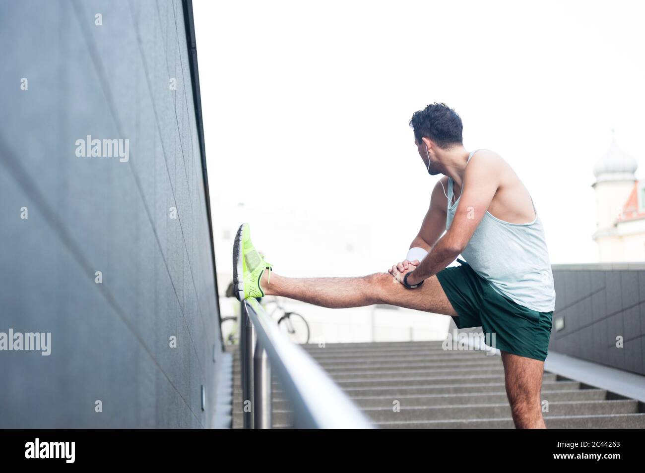 Young man stretching his leg on railing in the city Stock Photo - Alamy