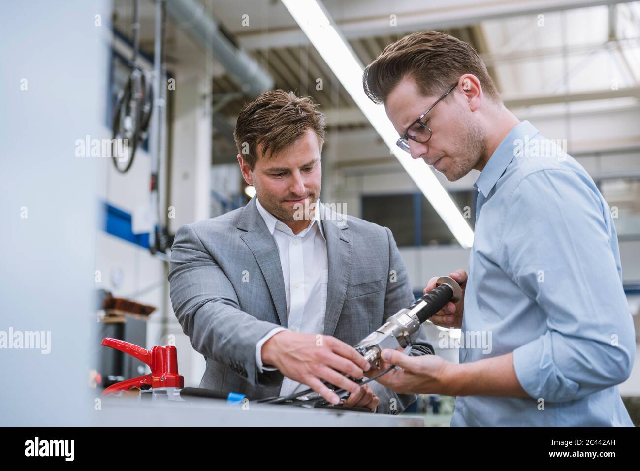 Two businessmen examining a product in a factory Stock Photo - Alamy
