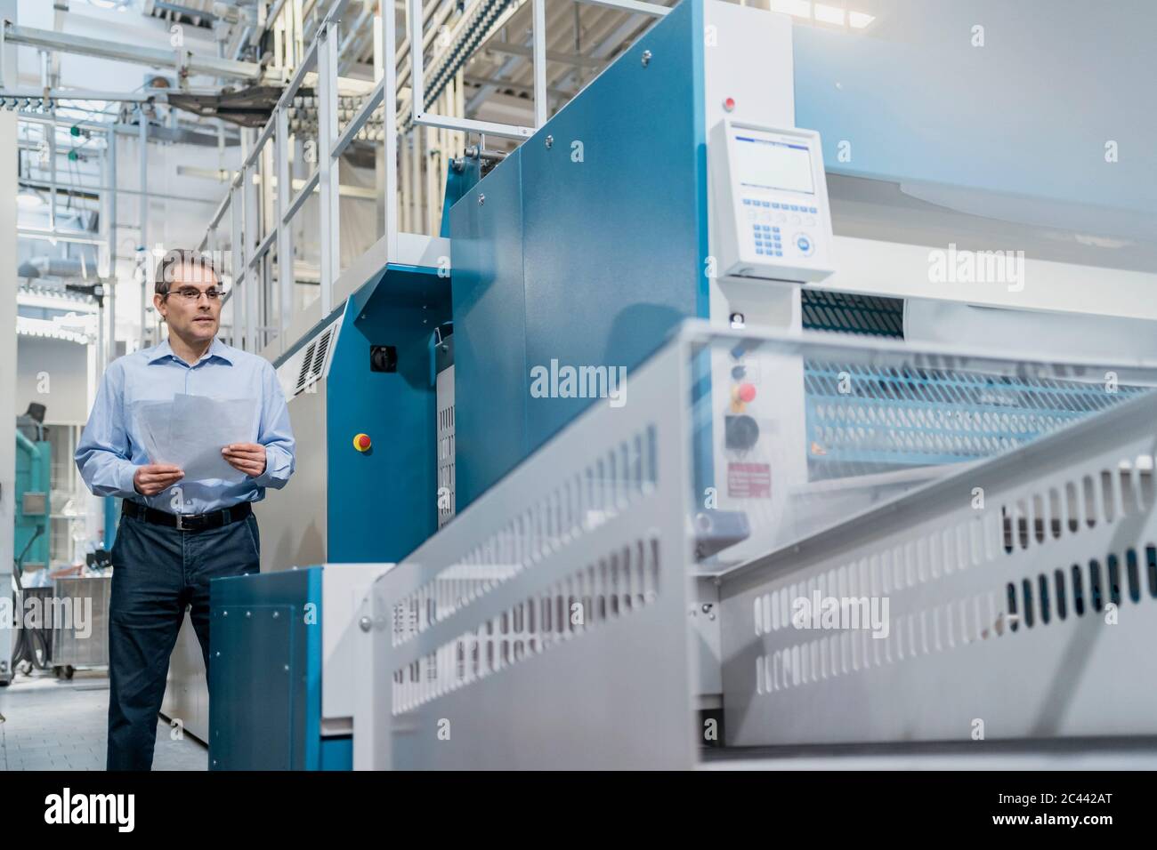 Mature businessman holding papers in a factory Stock Photo - Alamy