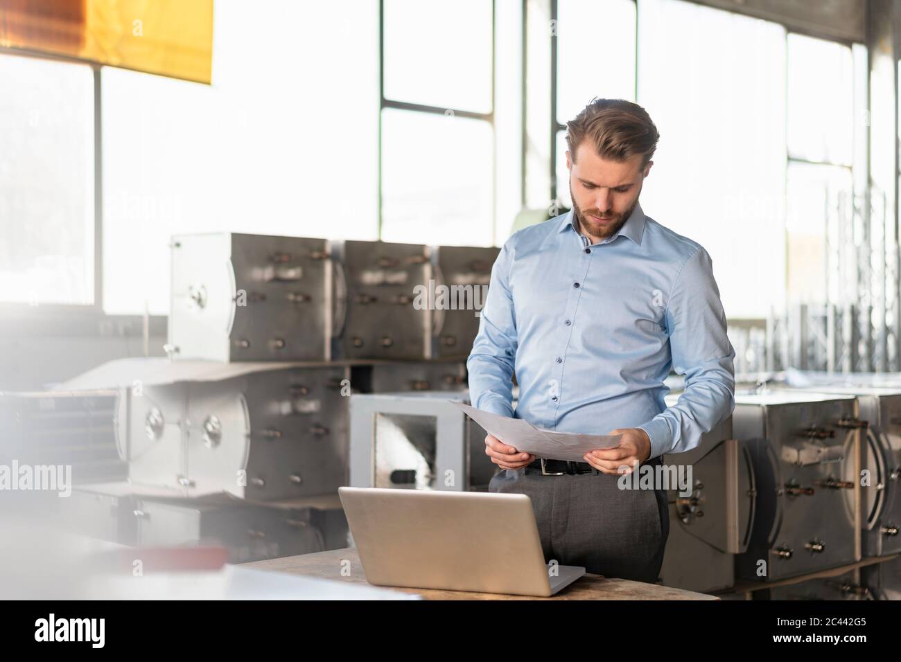 Young businessman reading papers in a factory Stock Photo - Alamy