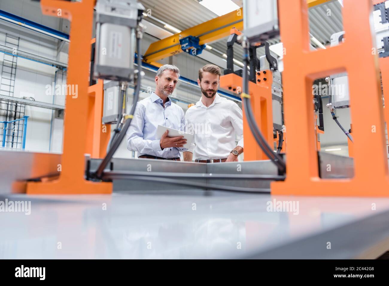 Two men with tablet looking at machine on factory shop floor Stock ...