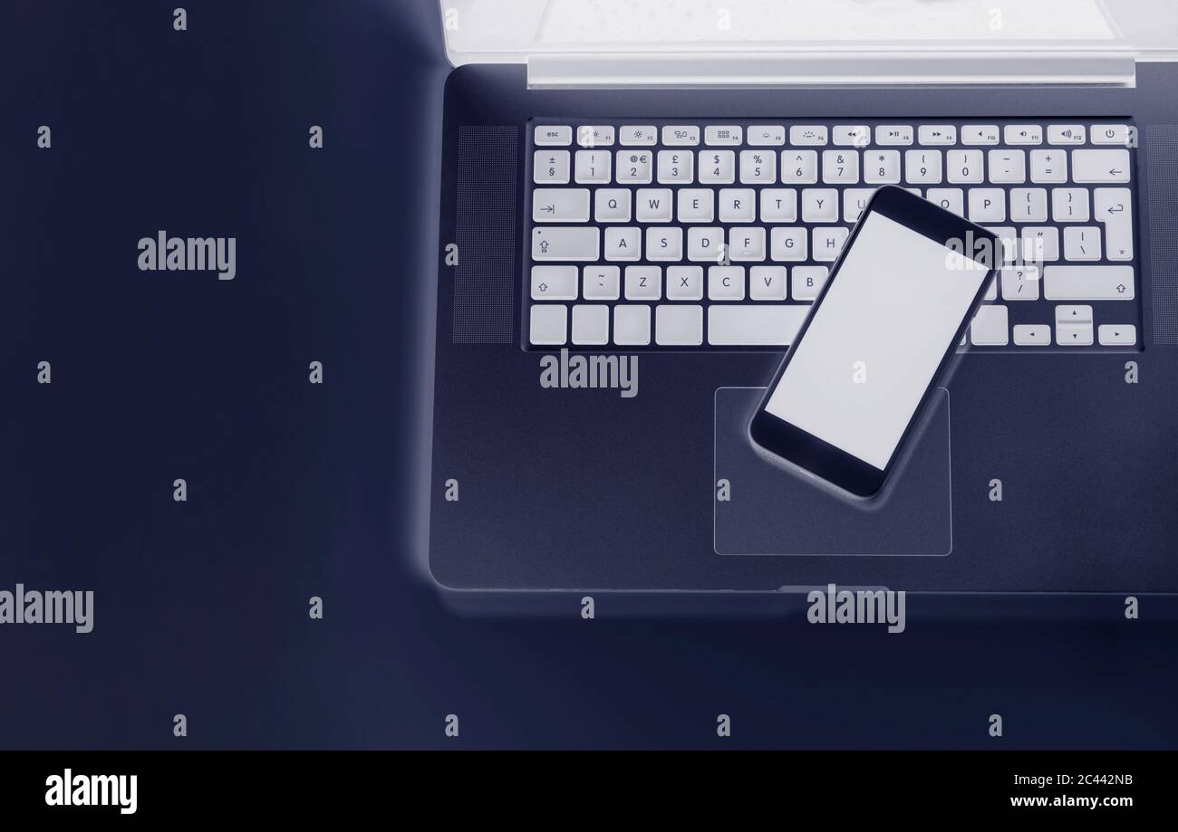 Overhead view of smart phone on laptop keyboard Stock Photo - Alamy