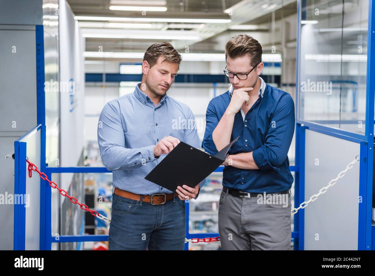 Two businessmen with clipboard in factory Stock Photo - Alamy