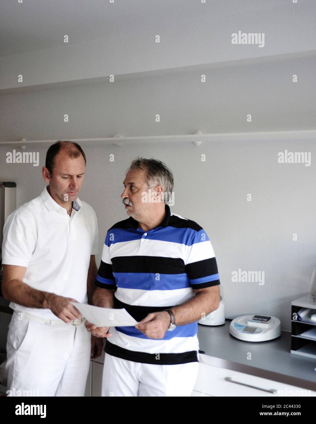 Two doctors with a paper discuss with each other Stock Photo - Alamy