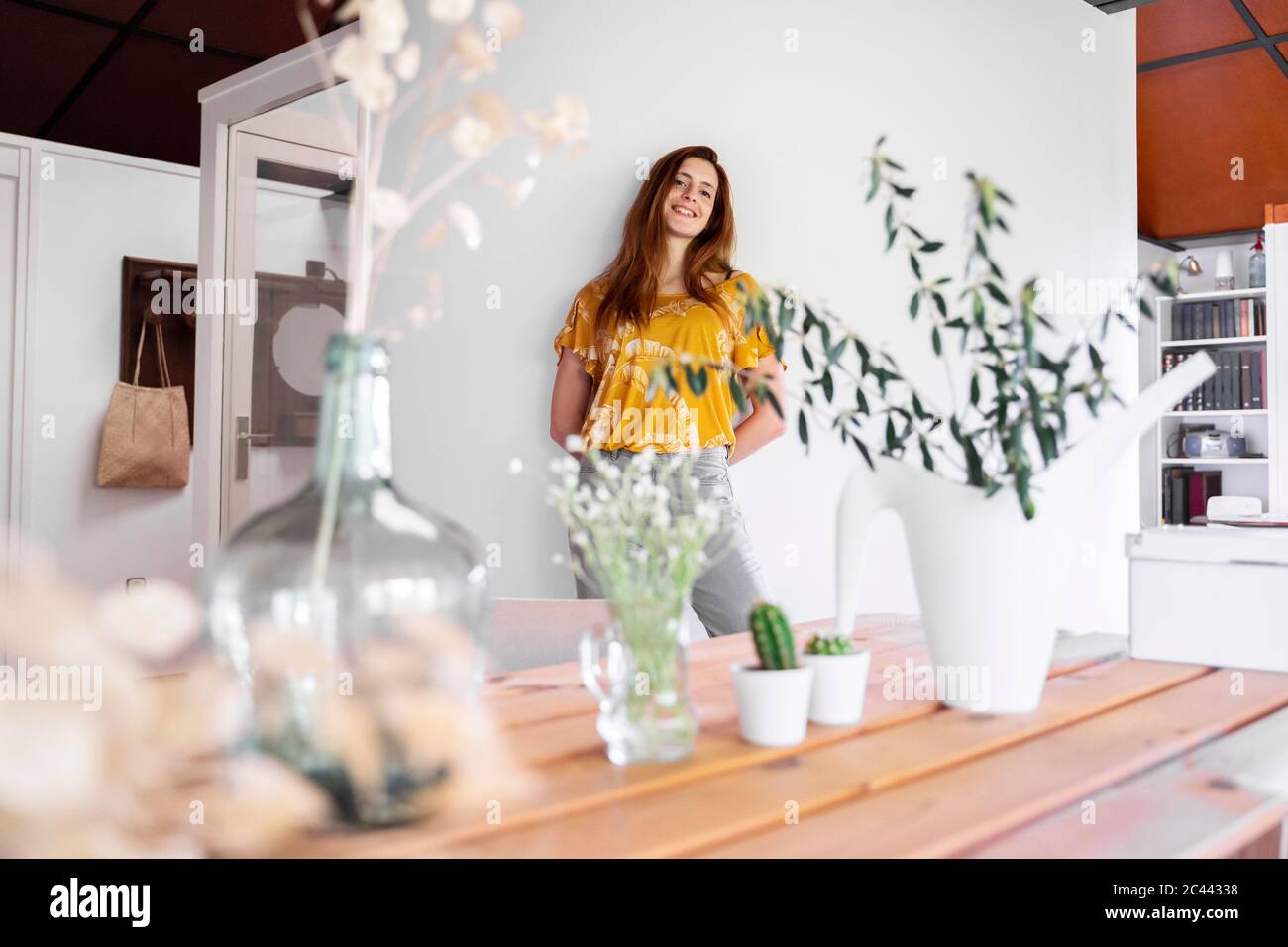 Smiling young woman standing against wall at home during curfew Stock ...