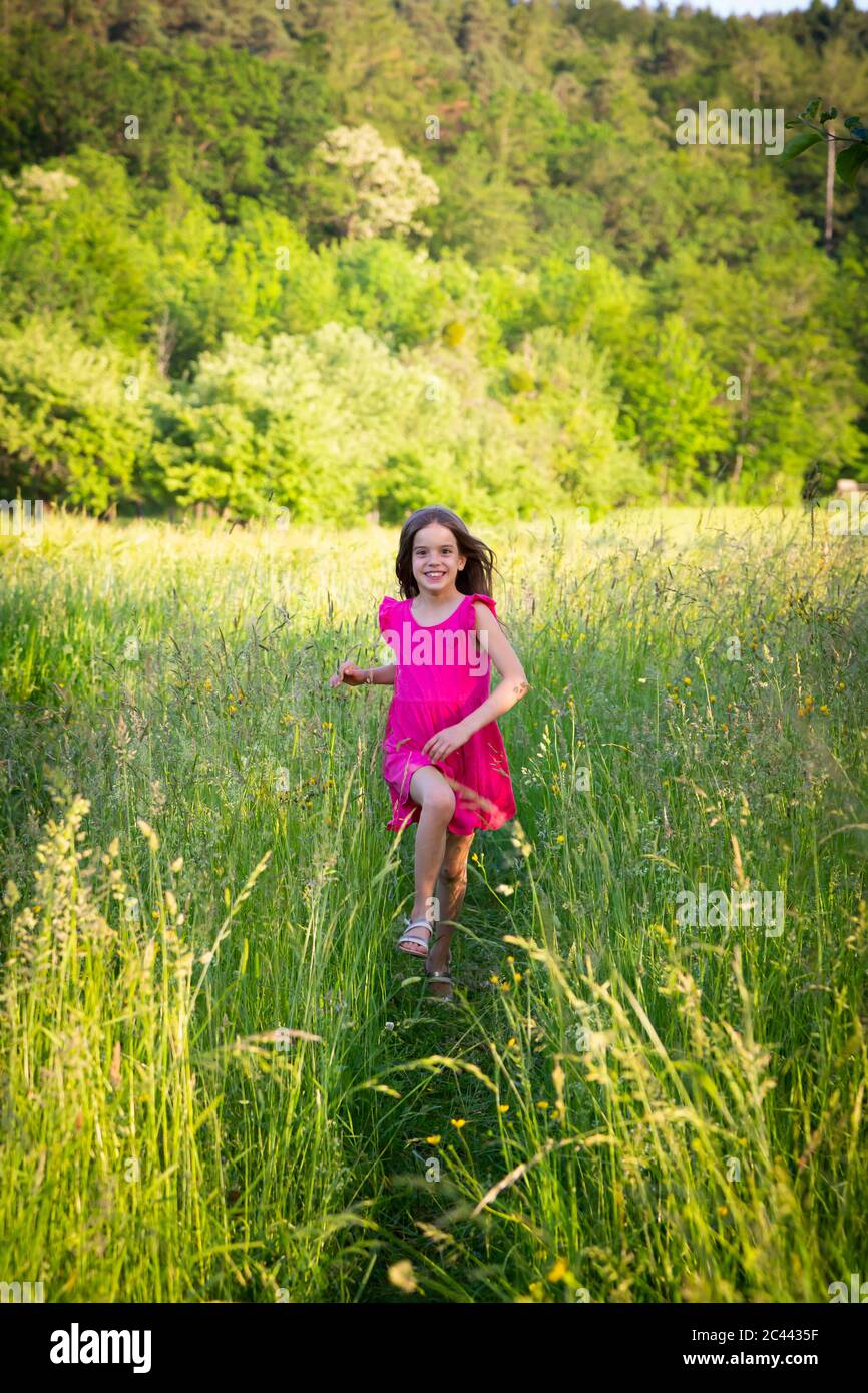 Portrait of little girl smiling while running toward camera across ...