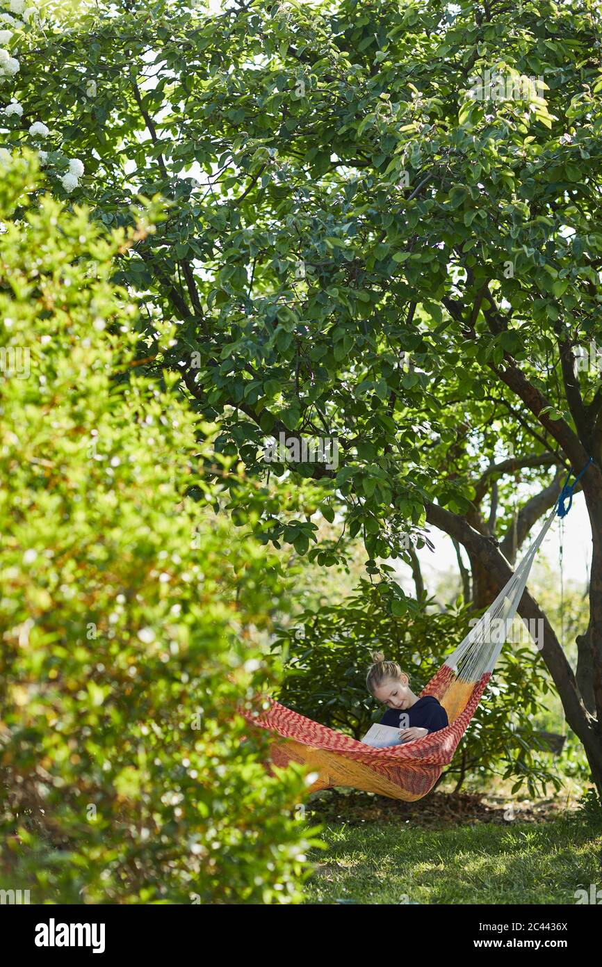 Girl in hammock reading a book Stock Photo - Alamy
