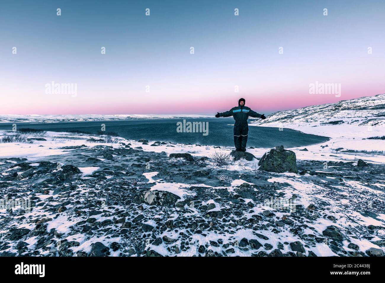 Man standing in coastal landscape in winter at Lakse Fjord, Lebesby ...