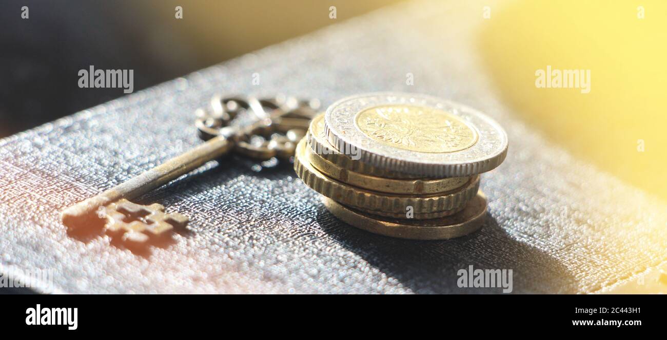 Old style rustic vintage key and stack of coins. Business startup or ...