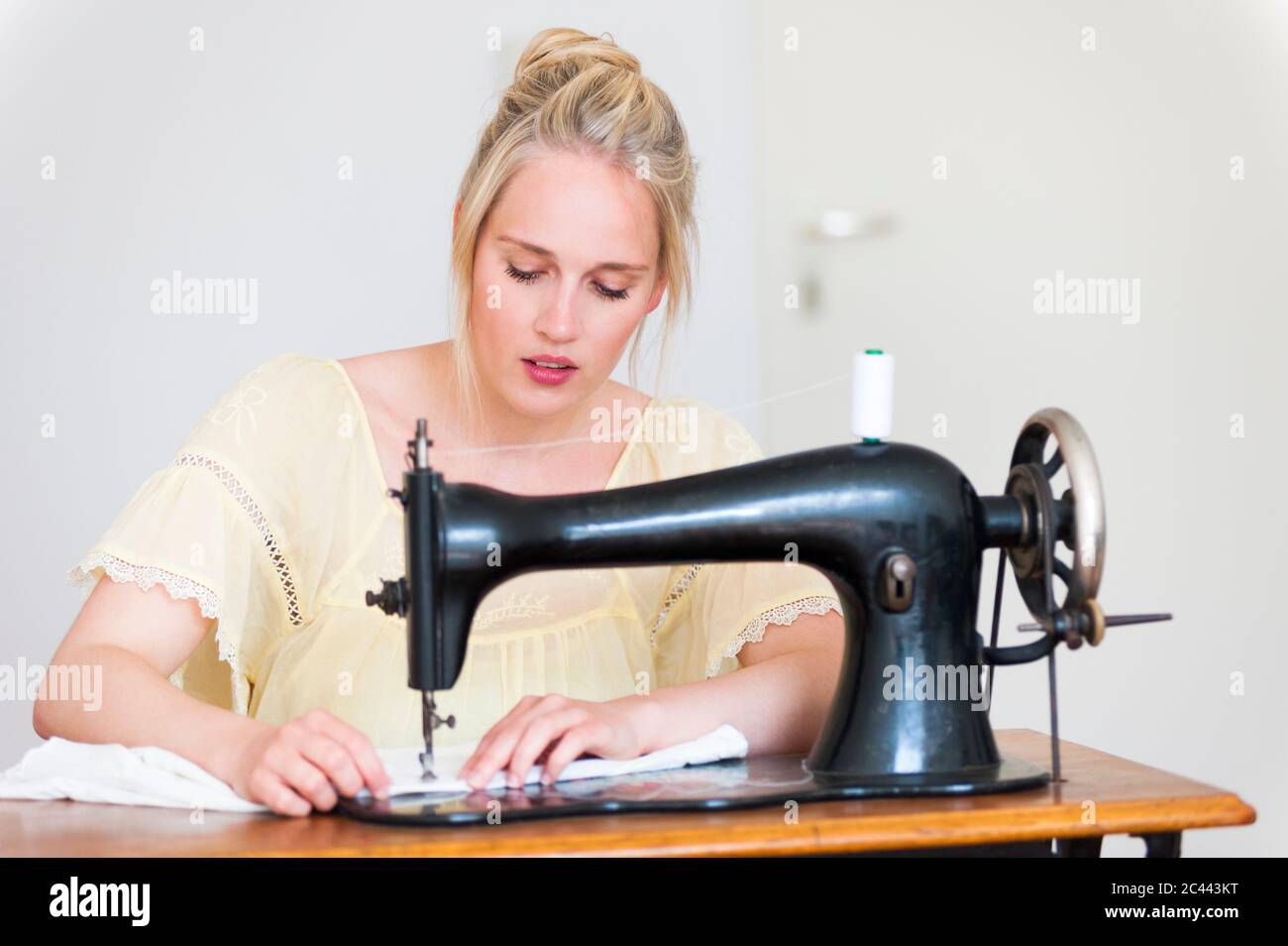 Portrait of blond young woman using old sewing machine Stock Photo - Alamy