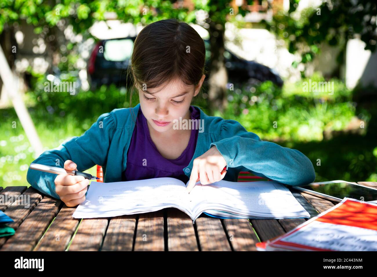 Girl sitting at garden table doing homework Stock Photo - Alamy