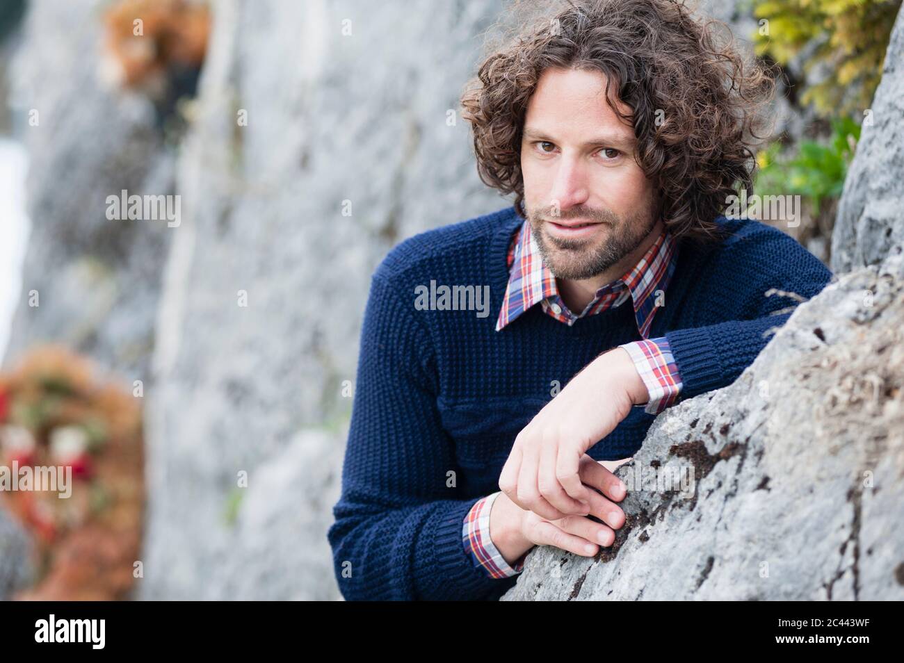 Portrait of confident handsome man leaning on rock Stock Photo - Alamy