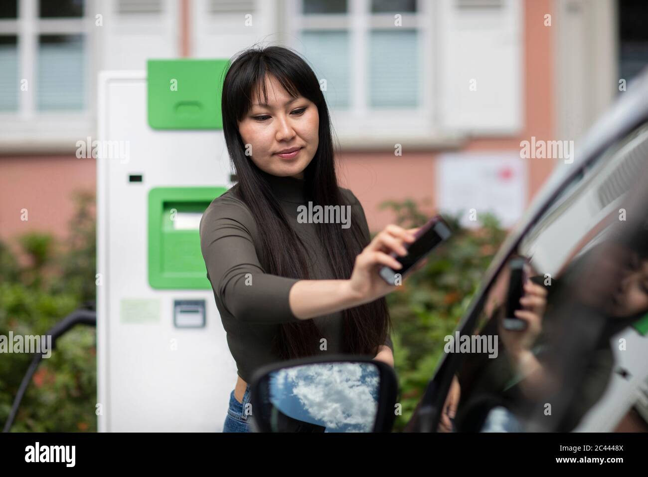 Carsharing, woman renting an electric car using smartphone Stock Photo ...