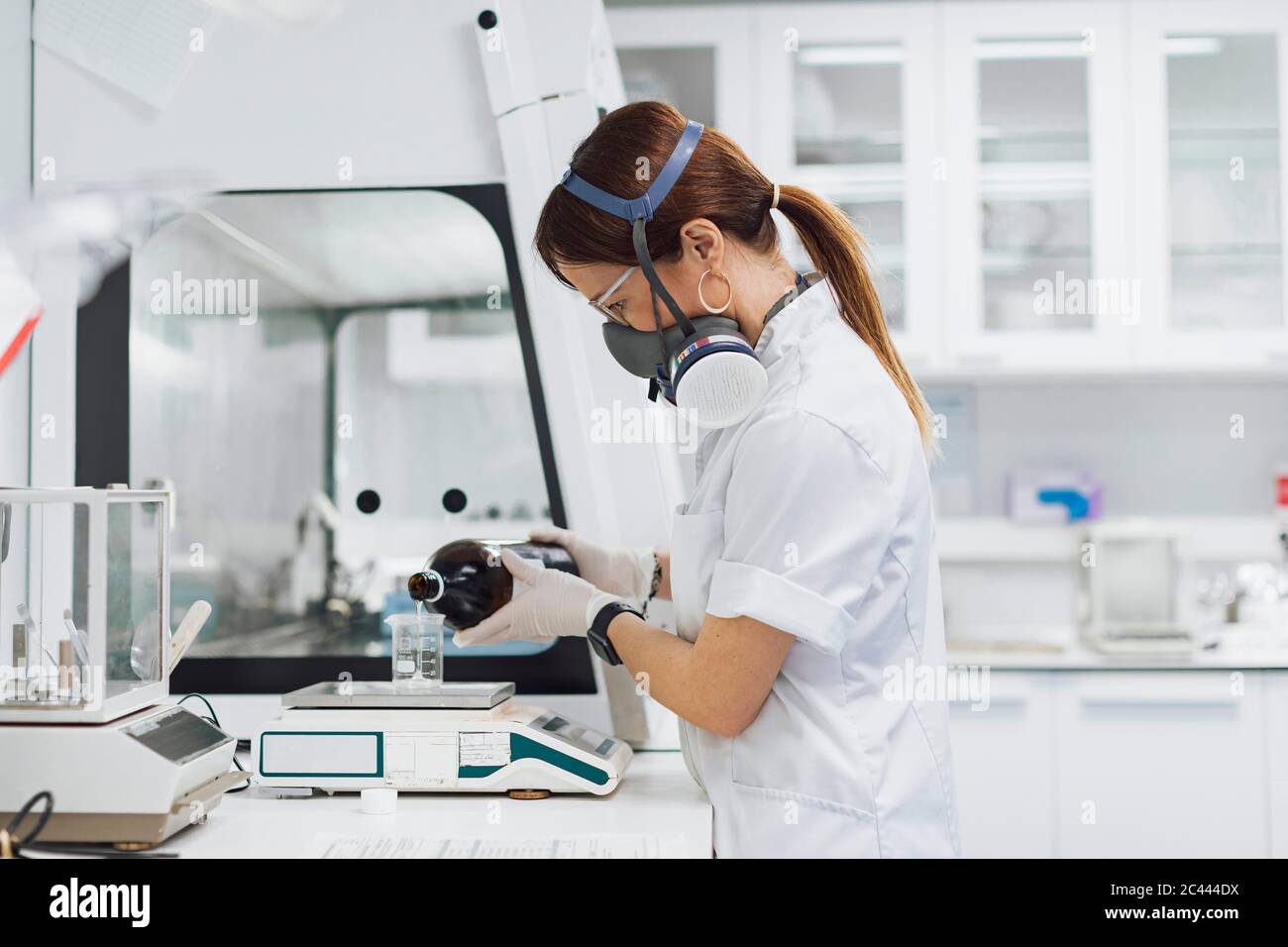 Doctor pouring chemical in beaker on weight scale while doing research ...