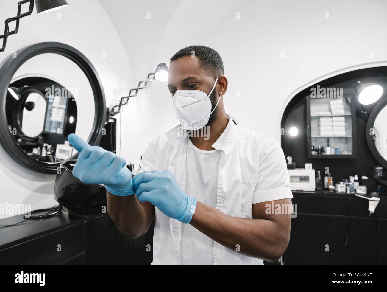 Barber wearing surgical mask putting on reusable gloves Stock Photo - Alamy