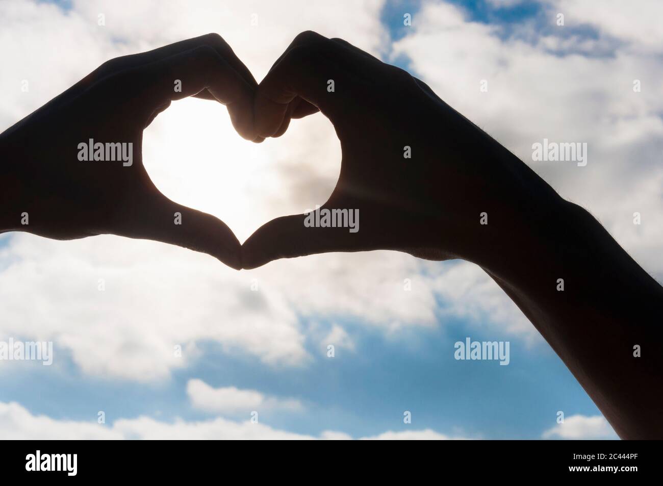 Hands shaping heart in front of cloudy sky, close-up Stock Photo - Alamy