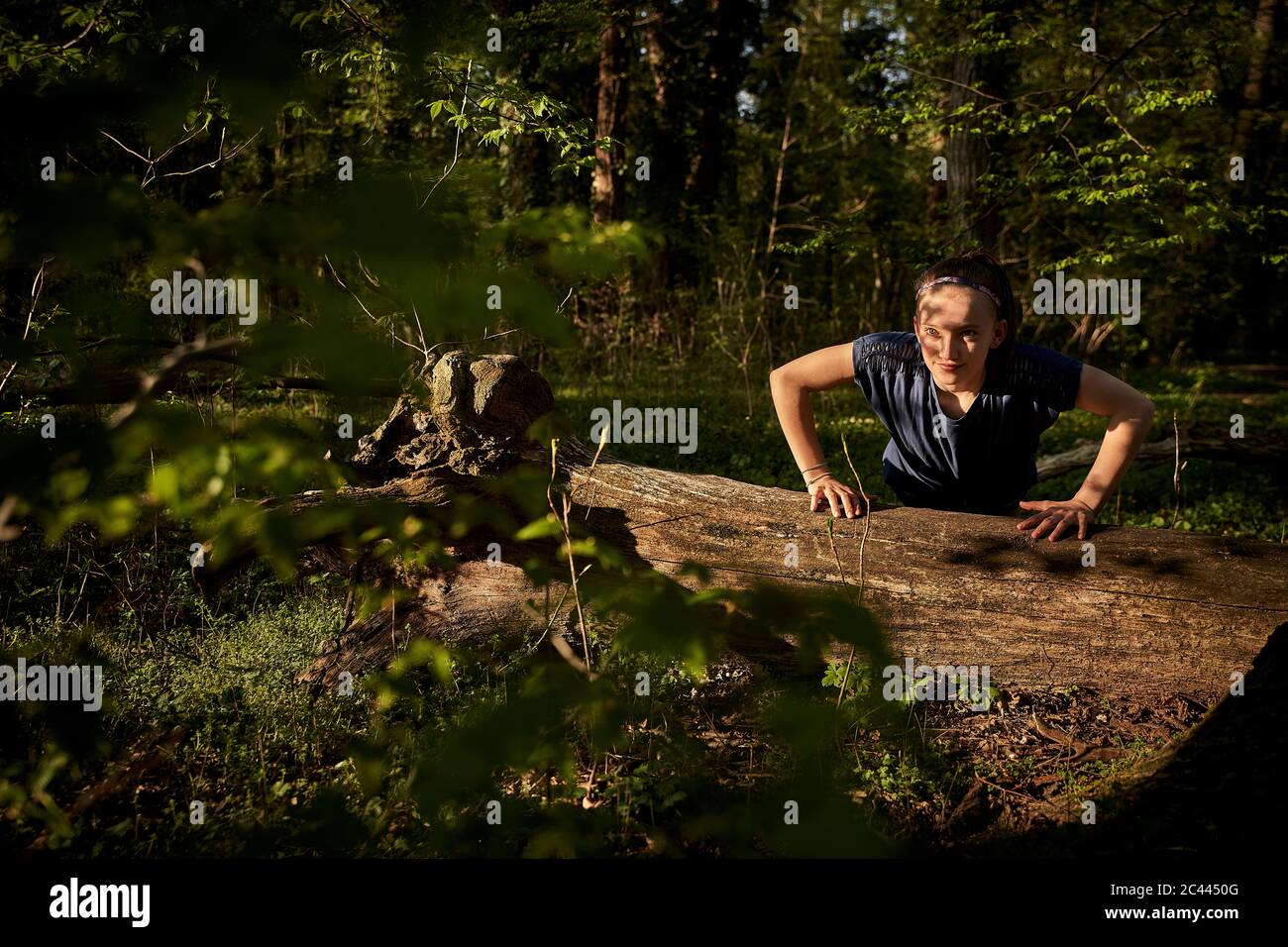 Girl doing push-ups on fallen tree in forest Stock Photo - Alamy