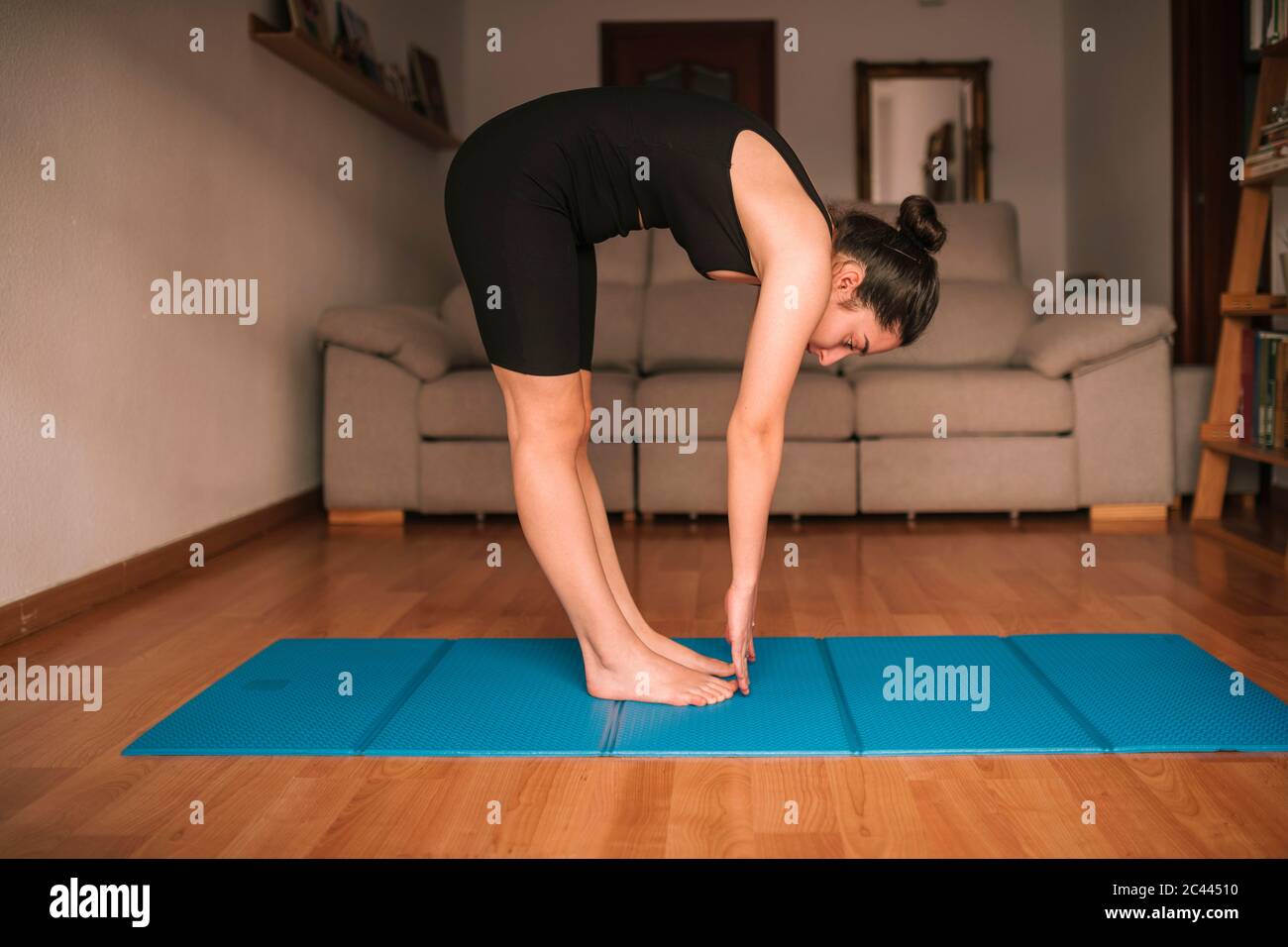 Young woman bending while practicing yoga in living room at home Stock ...