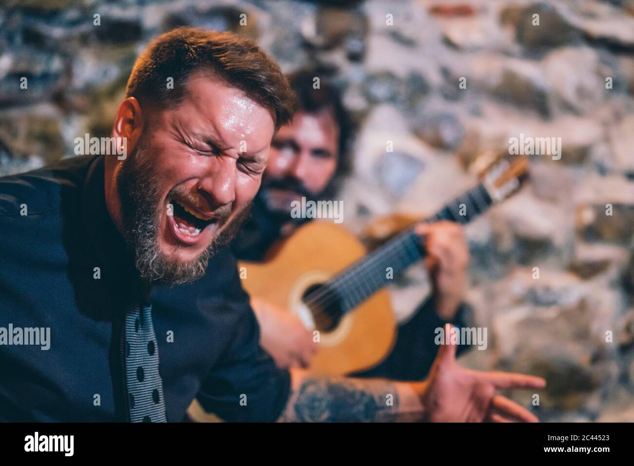 Close-up of singer with eyes closed singing while guitarist playing ...